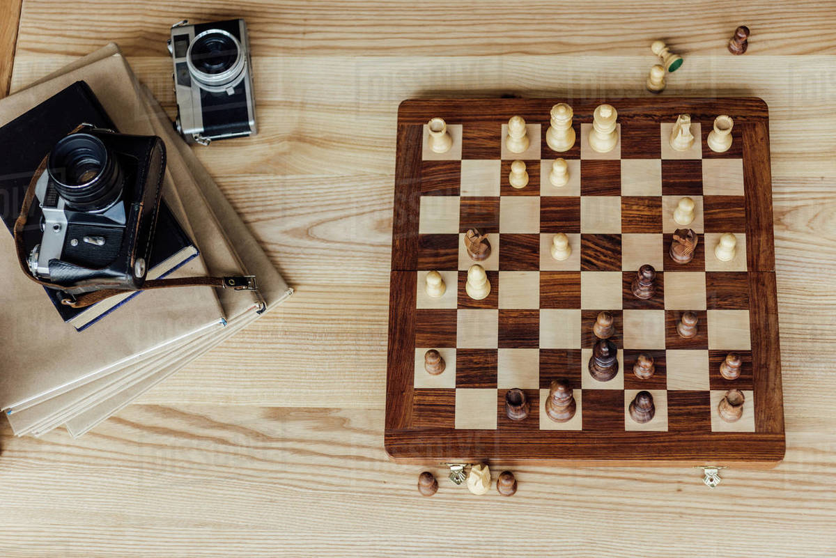 Above view of chess board set with old vintage cameras and books on ...