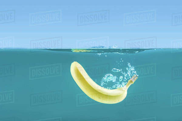 Side view of ripe yellow banana floating in water with bubbles - Stock ...