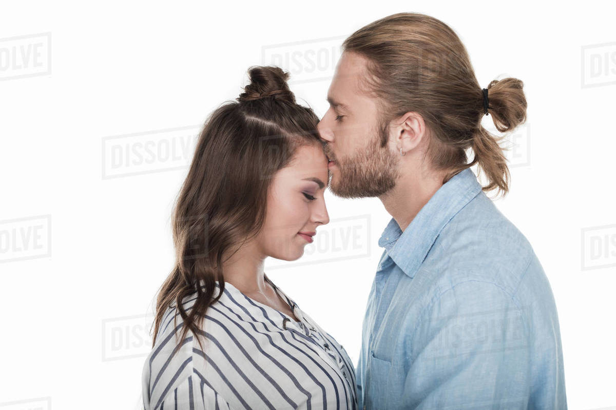 Side view of handsome young man kissing beautiful girl with closed eyes ...