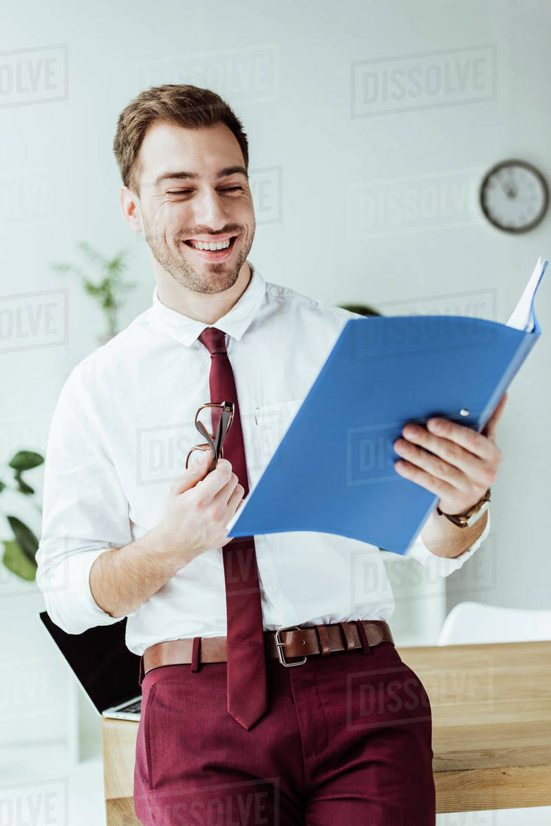 Handsome smiling businessman looking at folder with documents - Stock ...