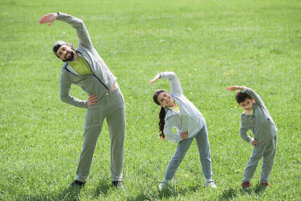 Father with daughter and son doing physical exercise on grass - Royalty ...
