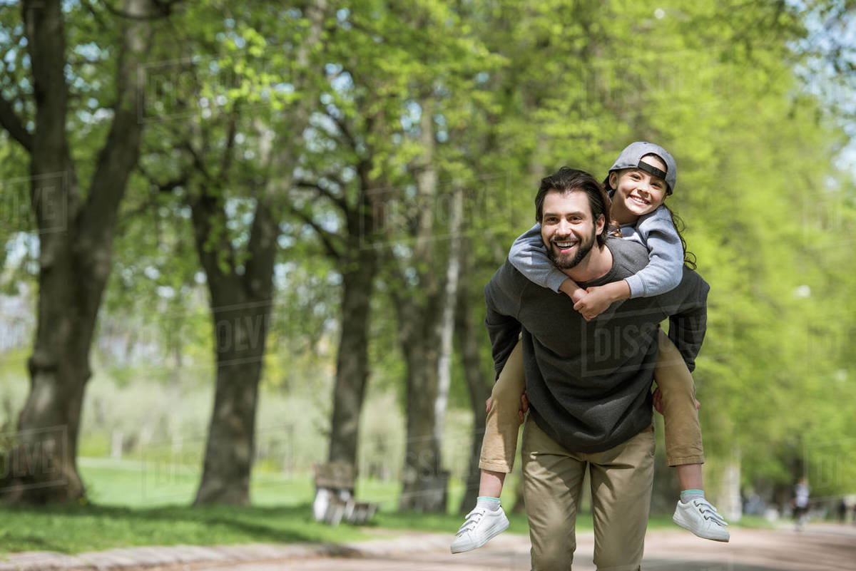 Happy father doing piggyback ride to daughter in park - Royalty-free ...