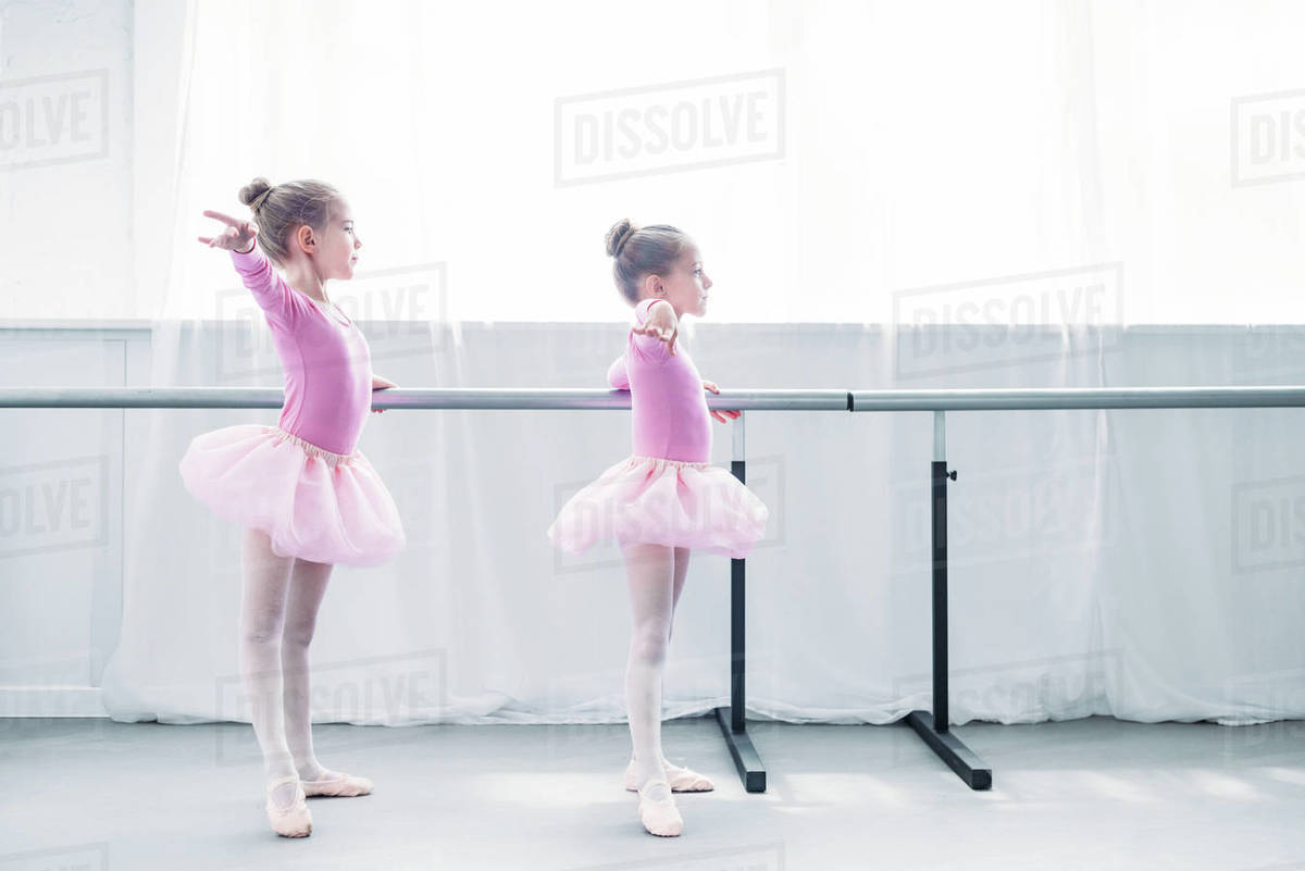 Side view of beautiful little kids in pink tutu skirts practicing ...