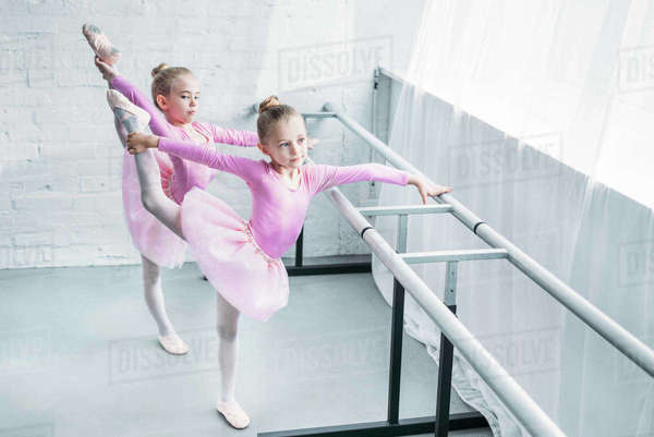 High angle view of cute little ballet dancers stretching in ballet ...