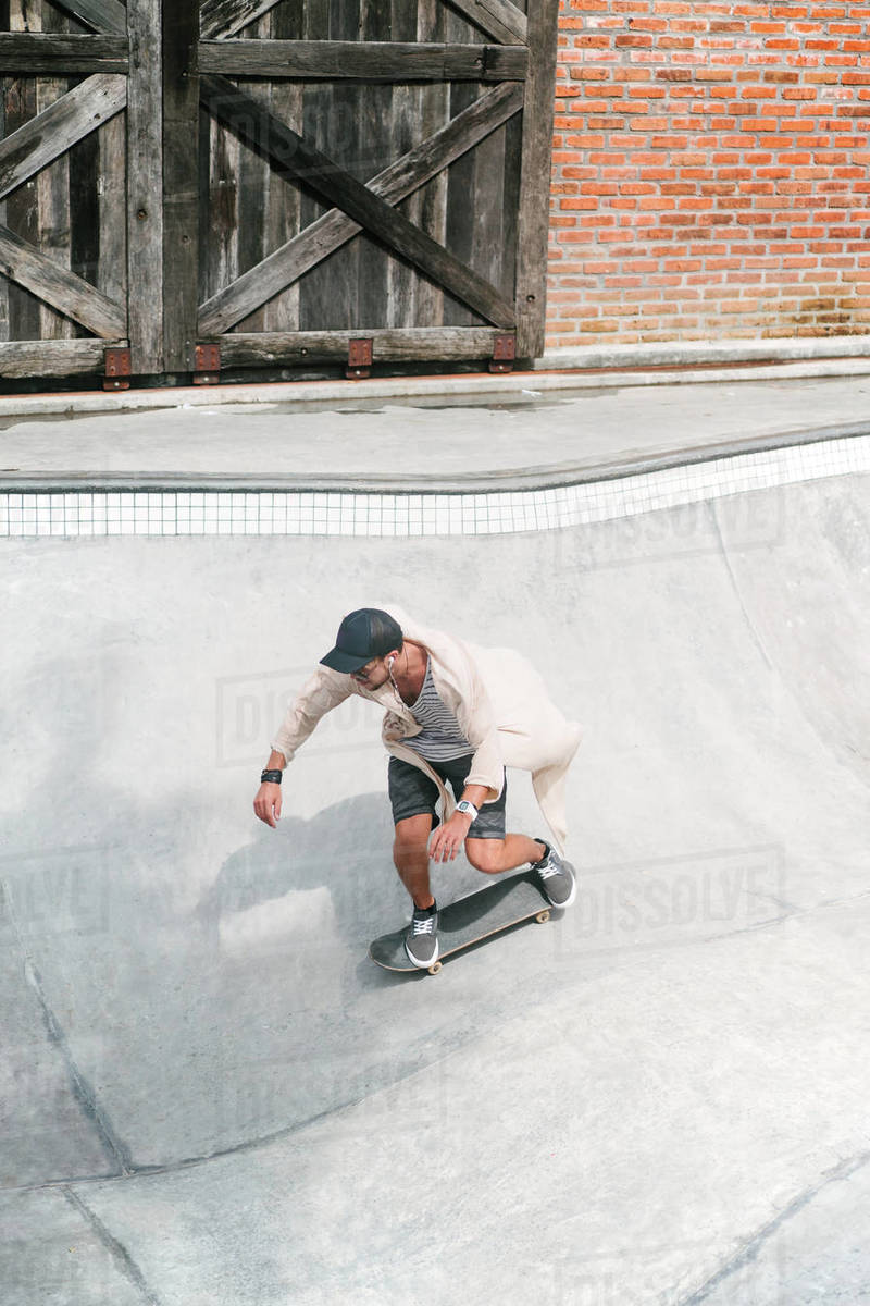 High angle view of young skater skating on longboard in pool at ...