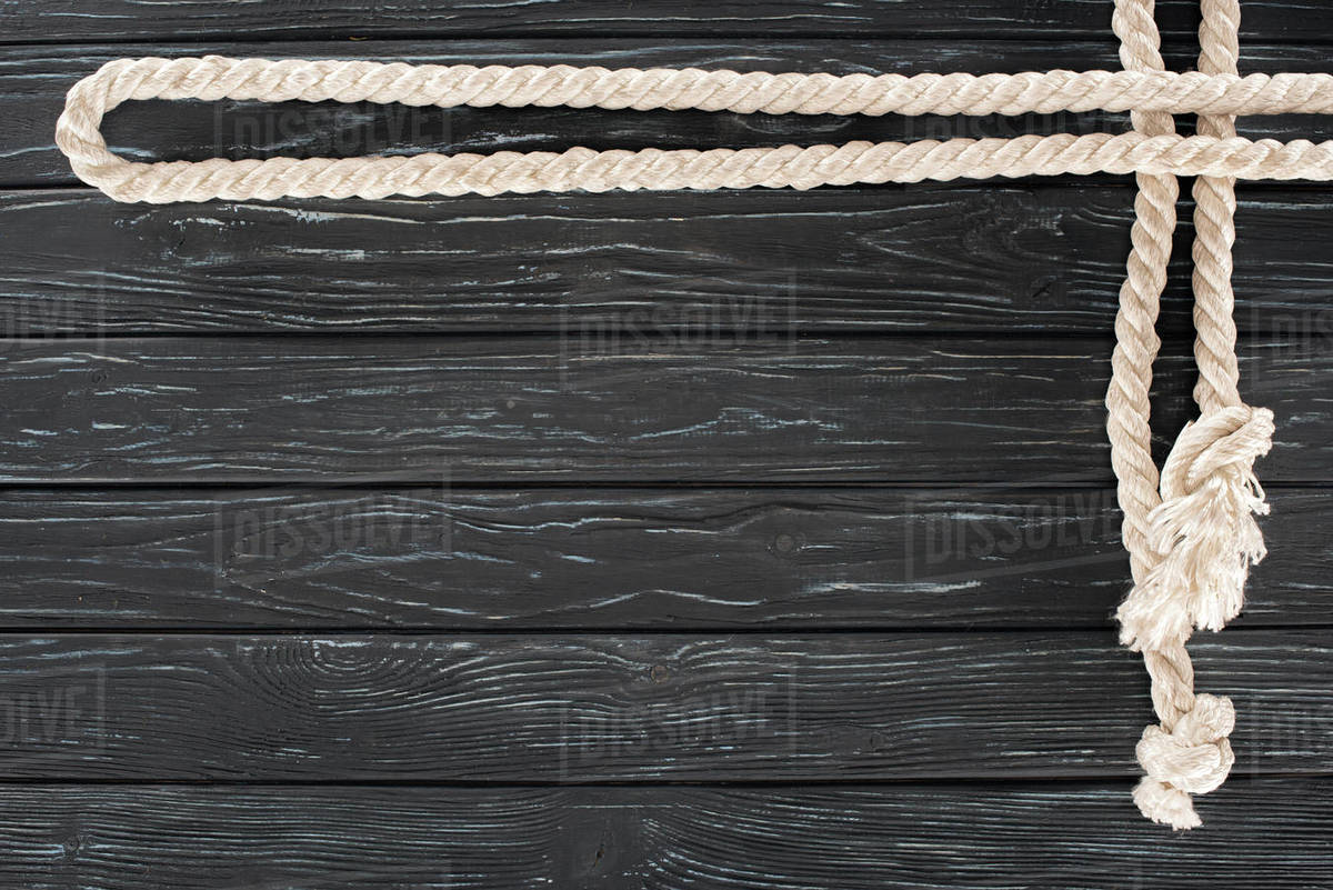 Top view of white nautical rope with knots on dark wooden tabletop ...