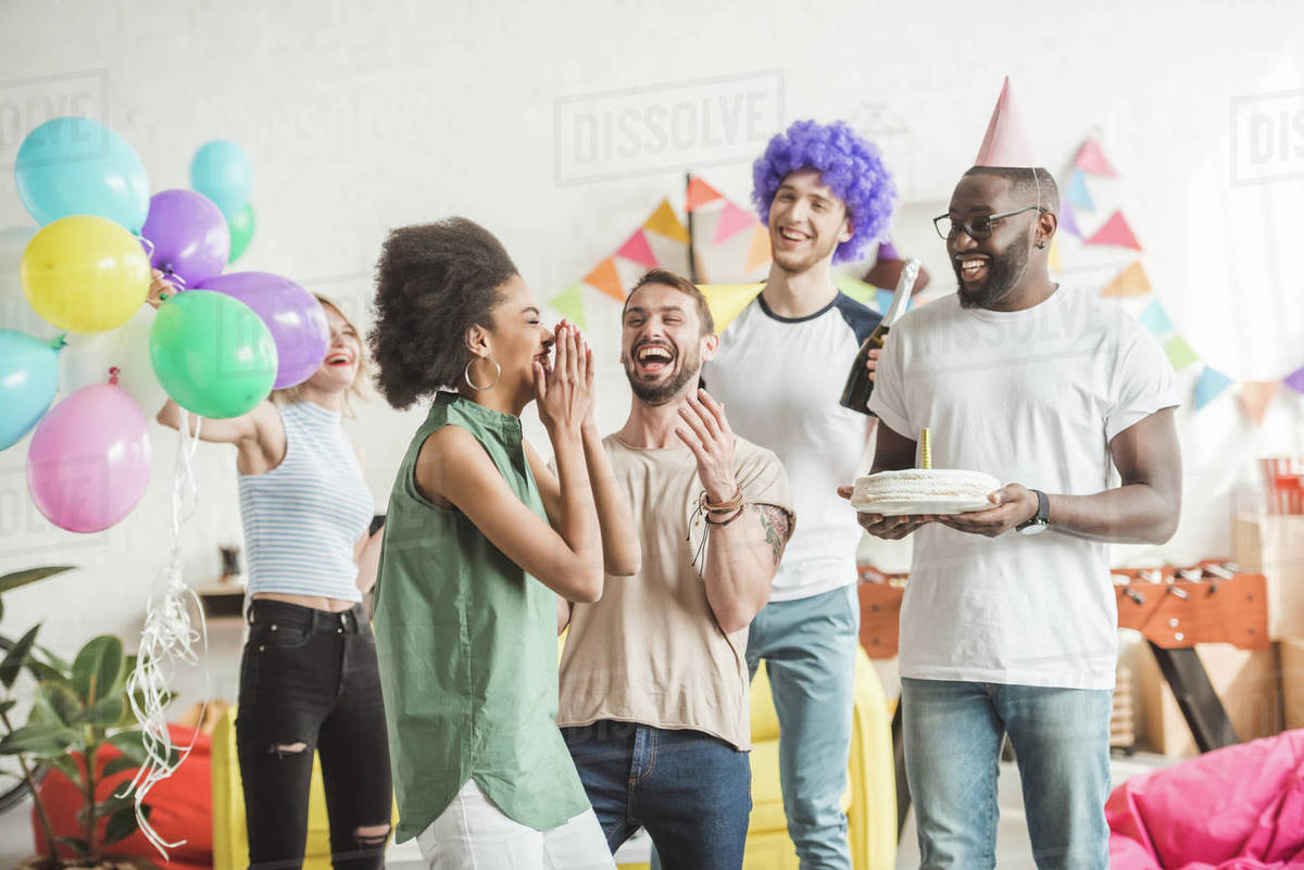 Happy young men and woman celebrating with birthday cake on surprise ...