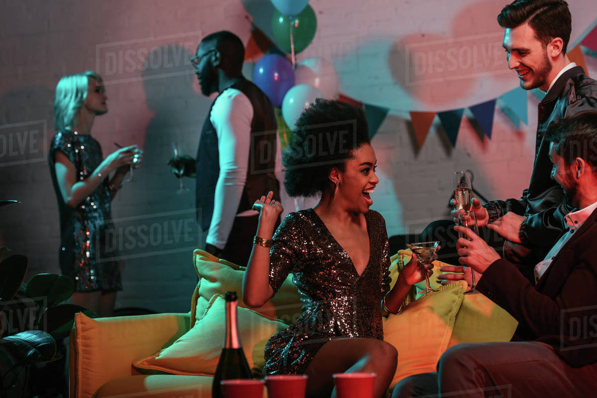 Cheerful young people enjoying drinks at talking at party - Royalty ...