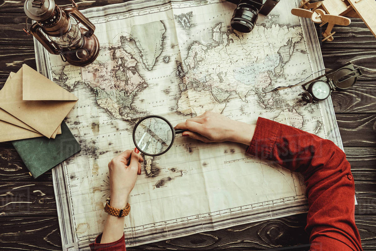 Partial view of woman with magnifying glass looking for destination on ...