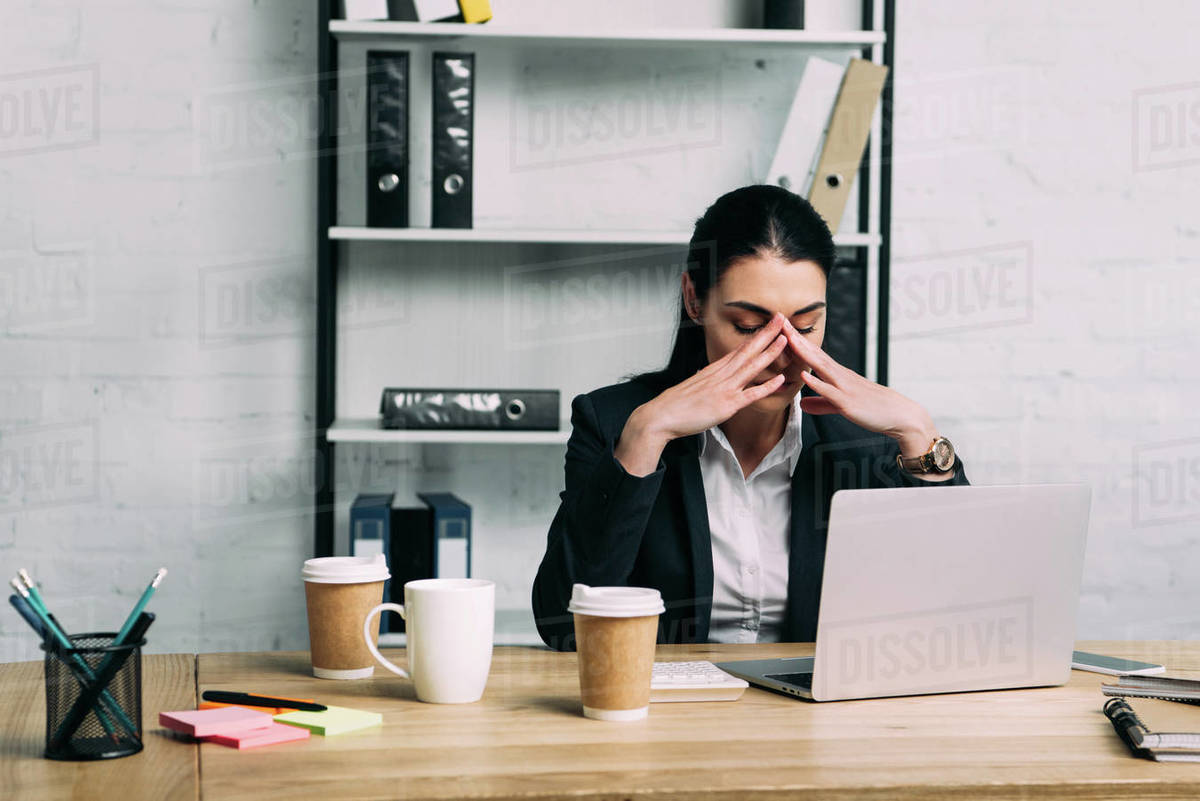 portrait of overworked businesswoman in suit at workplace with laptop ...