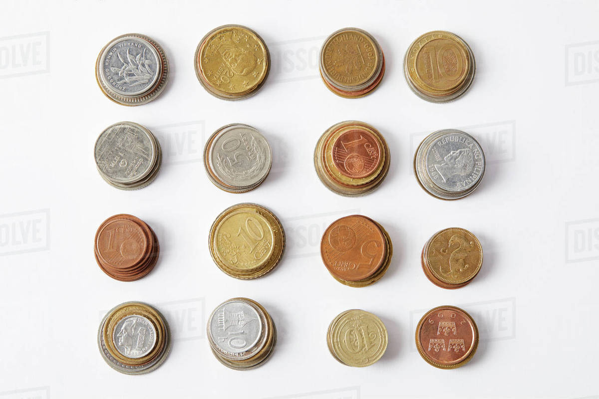 Top view of stacks of different coins on white - Stock Photo - Dissolve