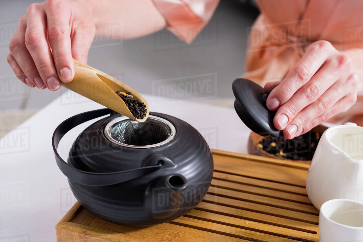 Cropped shot of woman making tea while having tea ceremony in morning ...