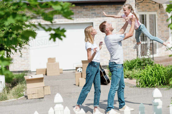 Father raising up daughter while mother standing near in front of their ...