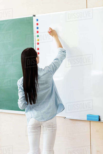 Rear view of asian student girl writing on whiteboard during lesson ...