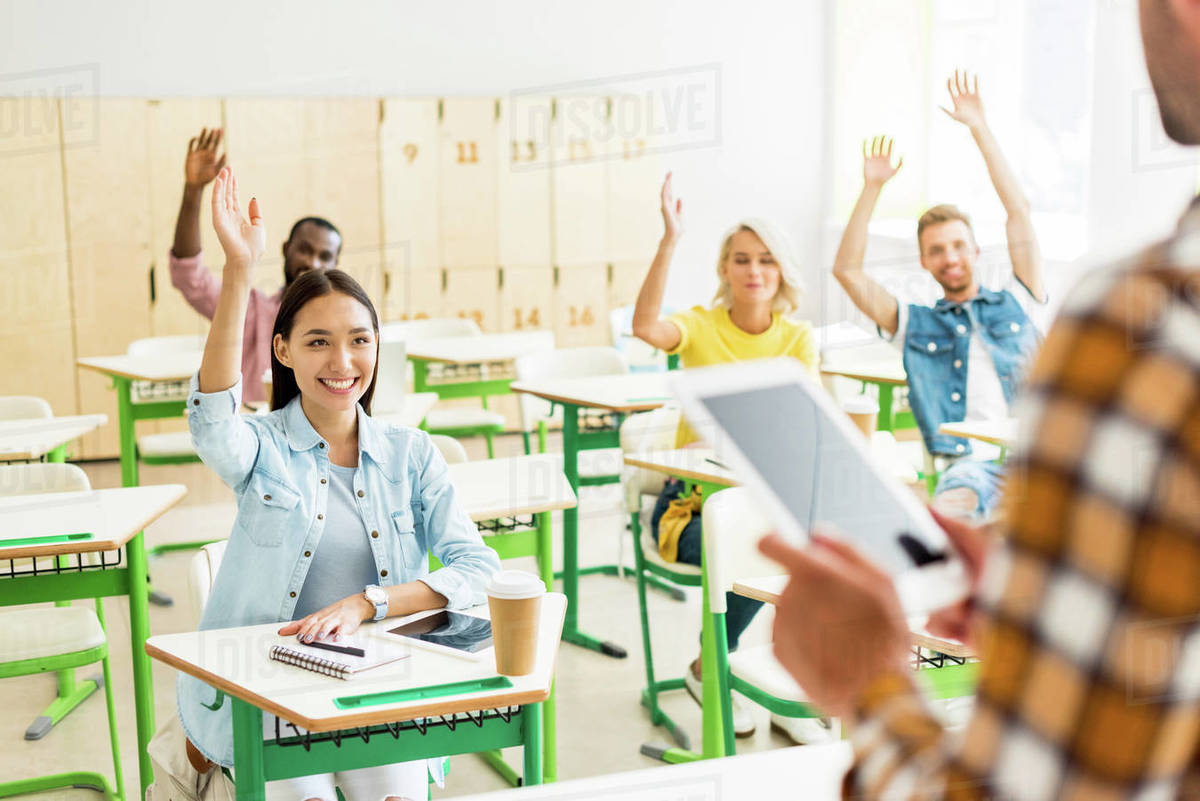 Young students raising up hands to answer on teachers question while he ...