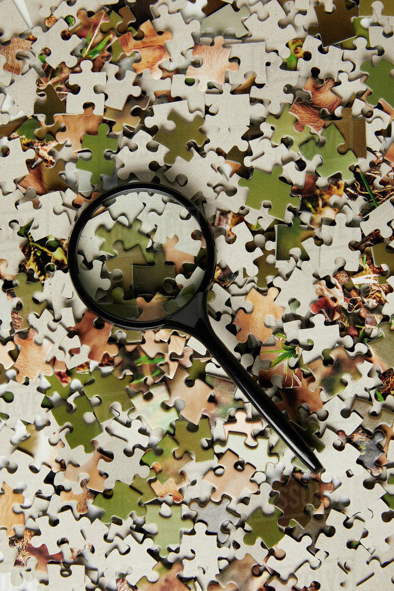 Top view of magnifying glass and jigsaw puzzle pieces on grey - Stock ...