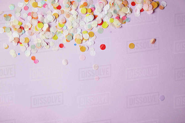 Top view of tiny confetti pieces on violet surface - Stock Photo - Dissolve