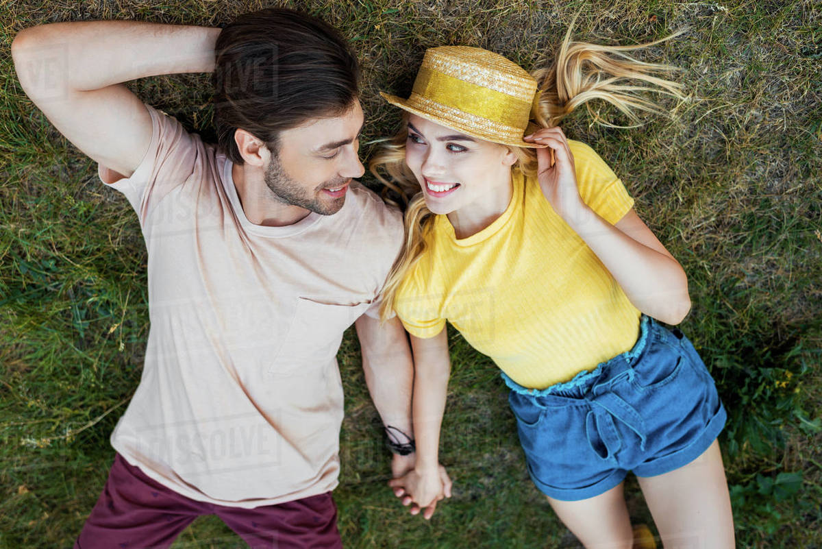 Overhead view of couple in love resting on green grass in park ...