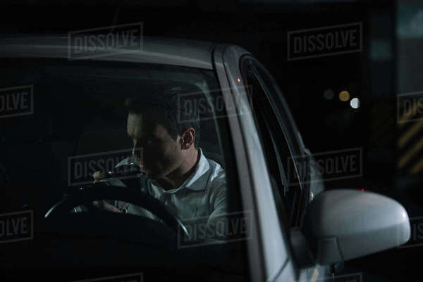 Serious undercover male agent doing surveillance by camera from his car ...