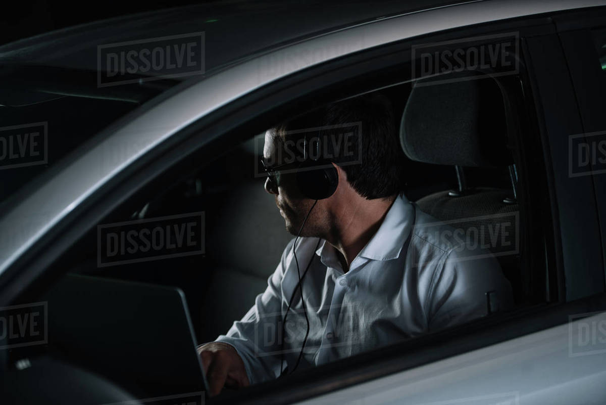 Side view of male private detective in headphones doing surveillance ...