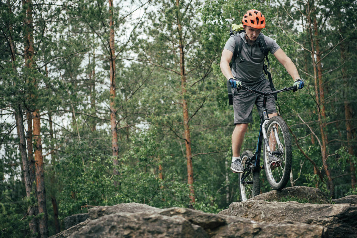 Male cyclist in protective helmet performing stunt on mountain bike in ...