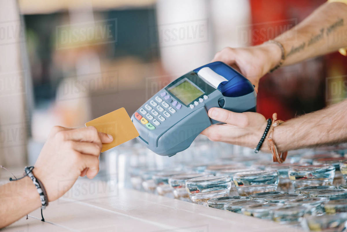 Cropped shot of young man paying with credit card on terminal at beach ...