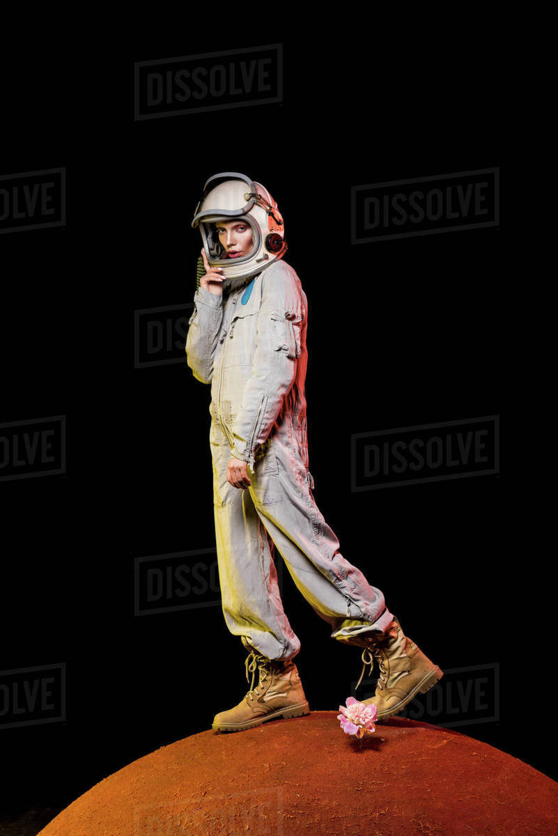 Cosmonaut in spacesuit and helmet standing on peony flower on planet ...