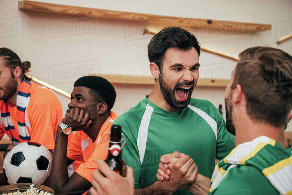 Excited football fans in green t-shirts celebrating victory while their ...