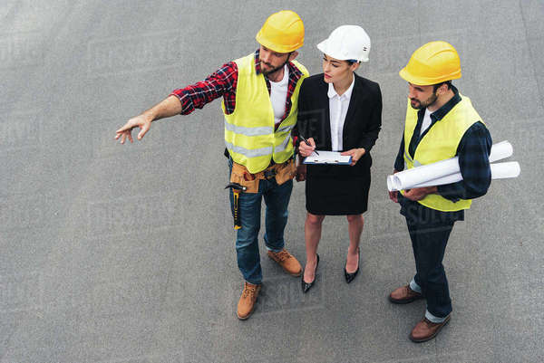 overhead view of female engineer and male workers with clipboard and ...