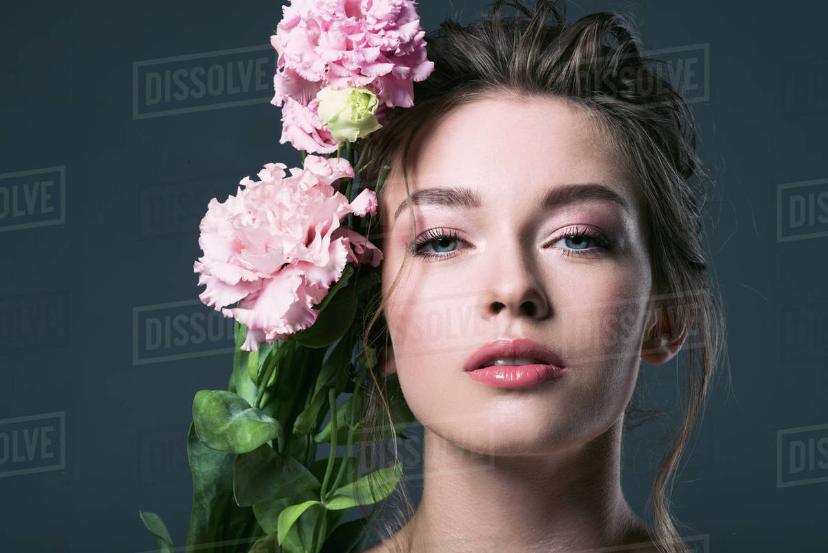 close-up portrait of beautiful young woman with pink eustoma flowers ...