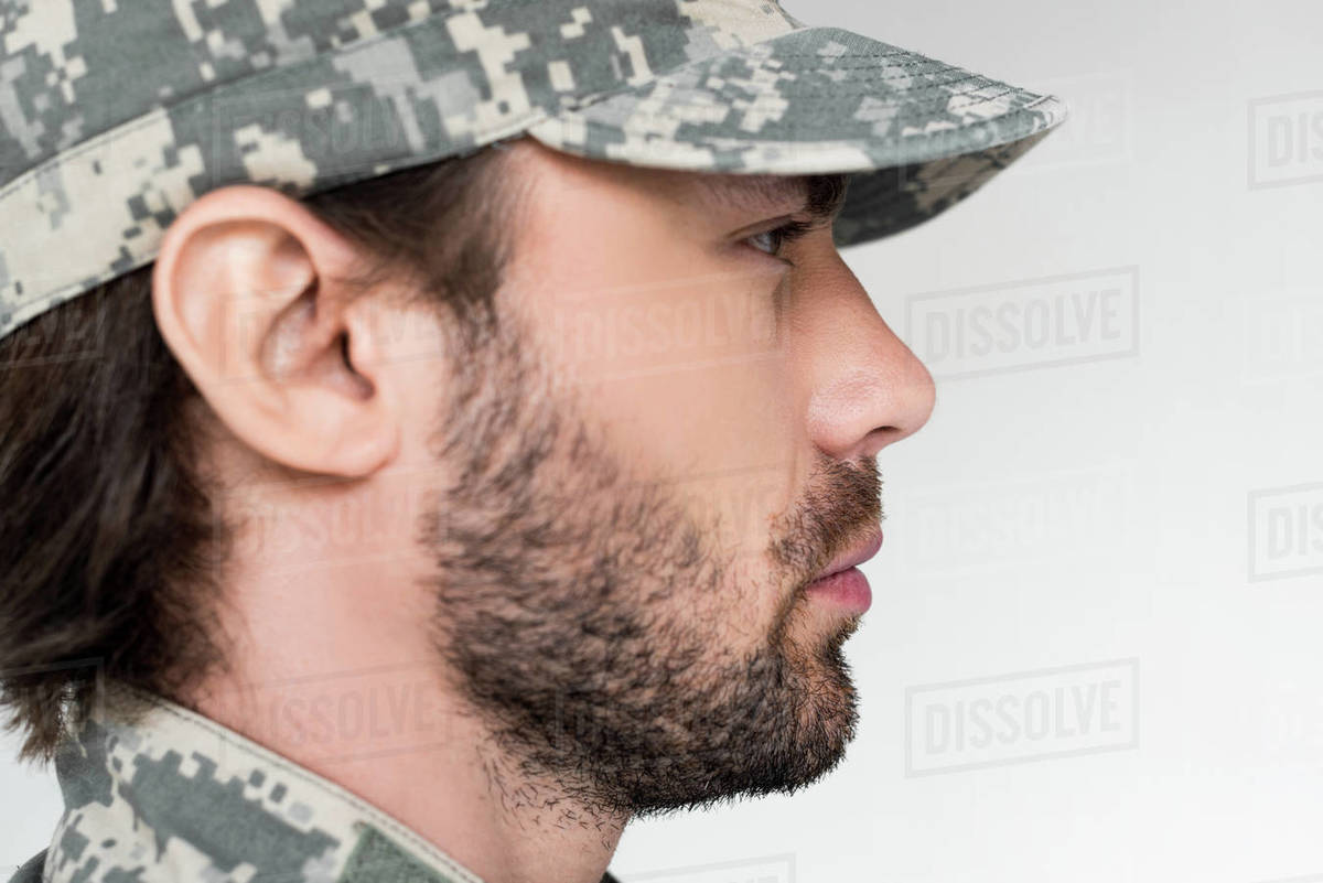 side view of confident bearded soldier in military uniform looking away ...