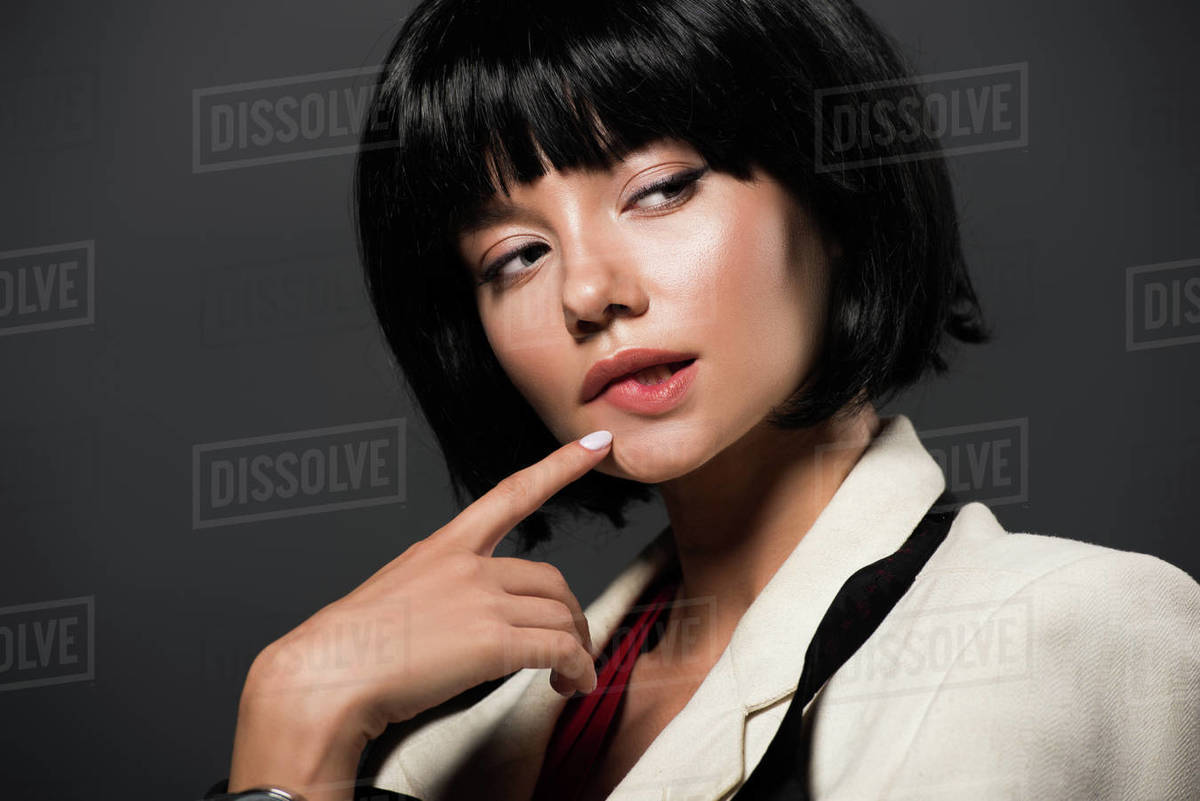 beautiful young woman in beige jacket and untied bowtie looking away ...