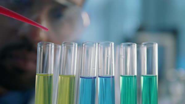 Close-up of chemical reaction - pipetting pink solution in colored ...