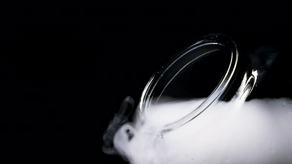 The fog from dry ice reacting with water eerily flows out of a glass ...
