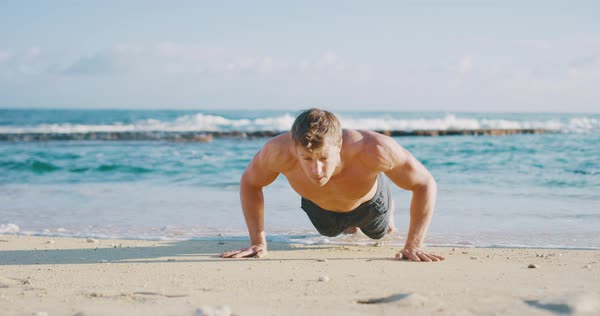 Young athletic man working out on the beach doing push ups, amazing ...