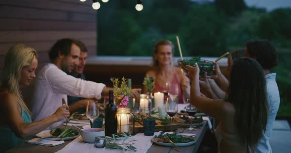 Scene of happy young friends eating dinner outside on the patio ...