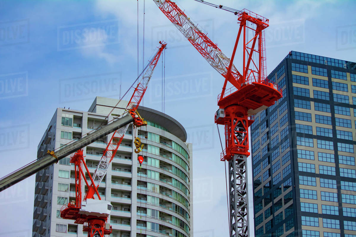 Working cranes on a modern office building under construction against ...