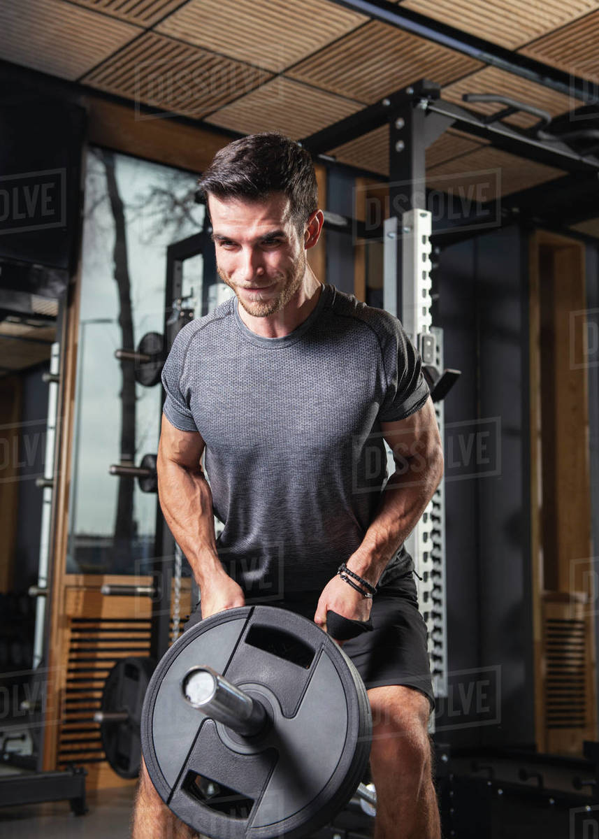 Young man working out with heavy weights at gym exercising with barbell ...