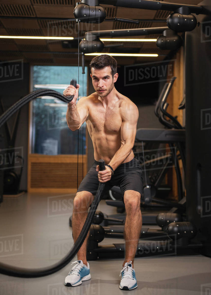 Shirtless man working out with battle ropes at gym - Stock Photo - Dissolve