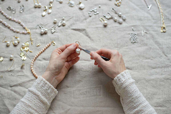 Jewelry designer working in studio with tools making pearl earrings ...