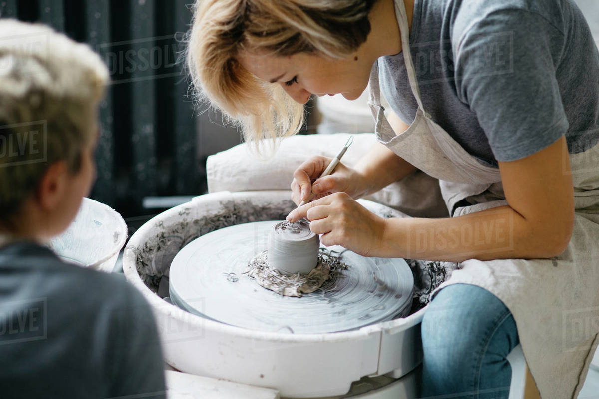 Ceramic working process with clay potter's wheel. Female colleagues ...