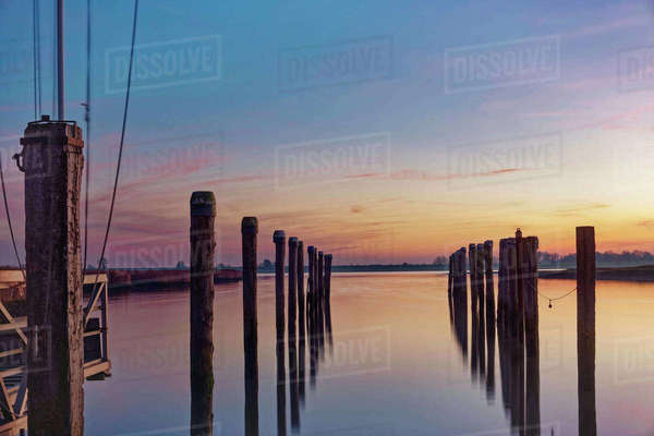 Rows of wooden posts in river Ems at sunset, East Frisia, Lower Saxony ...