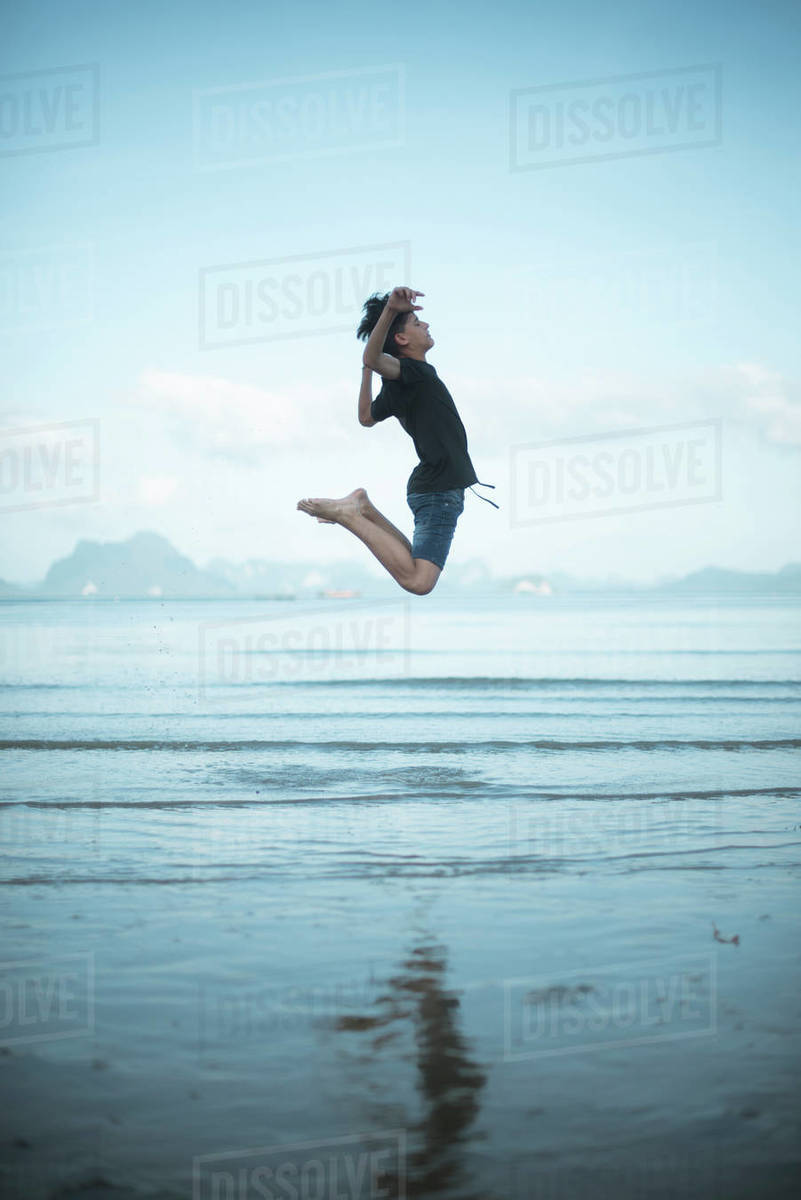 Teenage boy jumping in the air on the beach, Koh Yao, Phang Nga ...