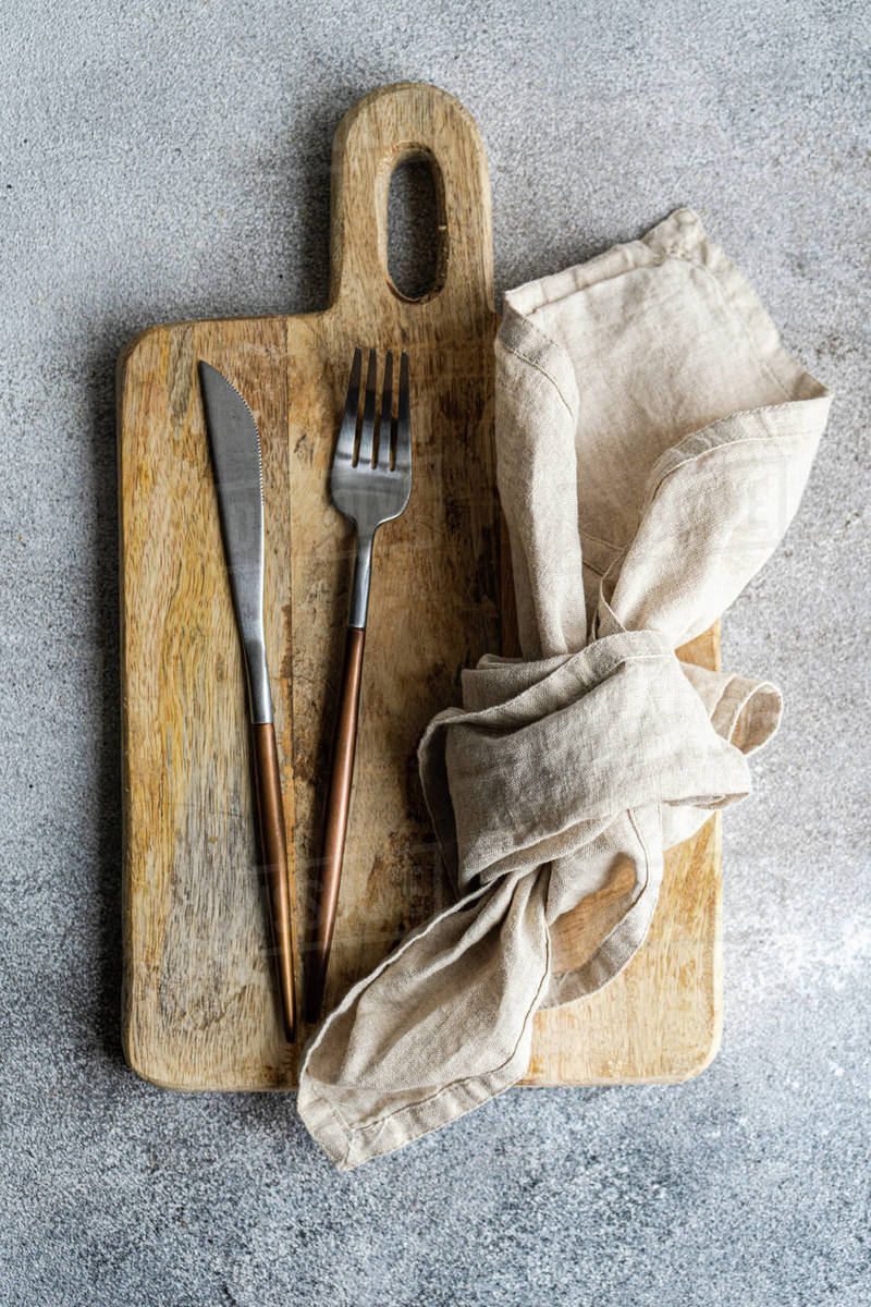 Overhead view of a cutlery set and napkin on a chopping board - Royalty ...