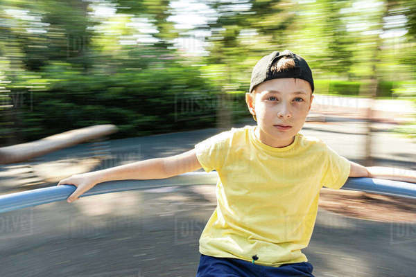 Boy spinning around on a carousel in a park in summer, Georgia ...