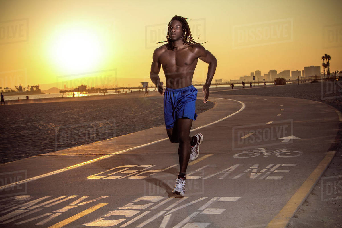 20 something runner at sunset on a path by the beach. Summer night run ...