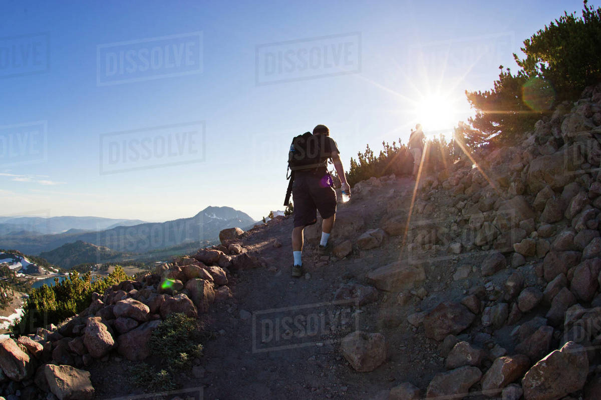 Hiker is hiking up a tall mountain in california at sunset. Great view ...