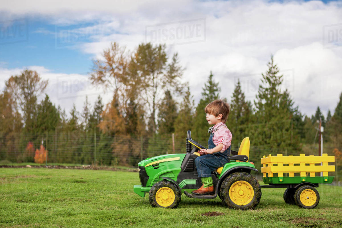 Boy driving a toy tractor - Stock Photo - Dissolve