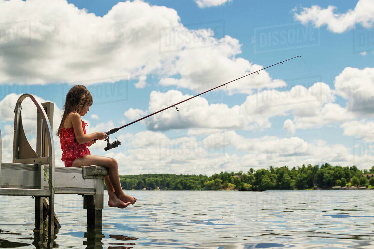 Girl sitting on dock fishing - Stock Photo - Dissolve