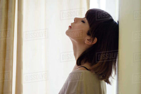 Portrait of a woman with head back leaning against a wall - Royalty ...